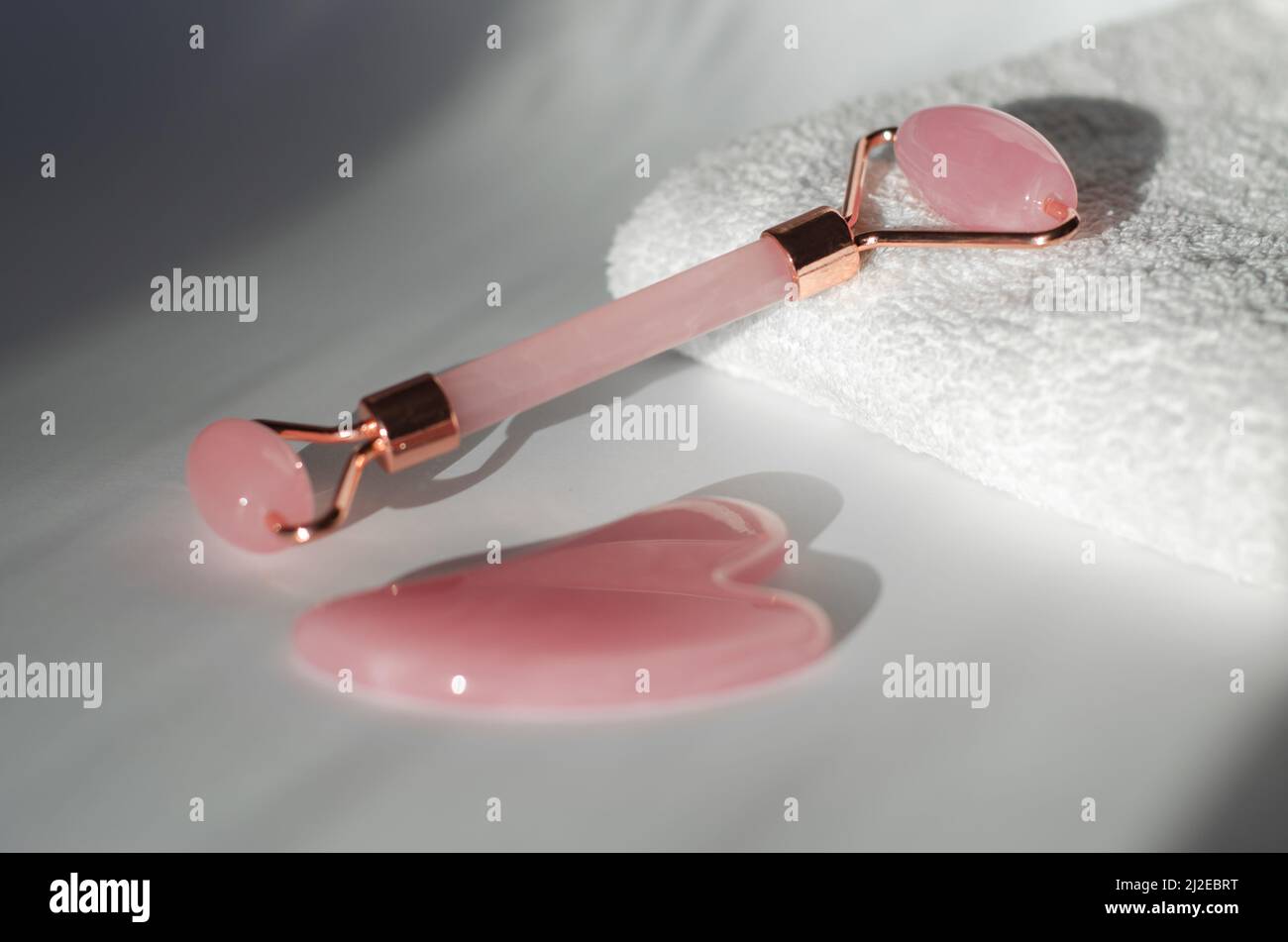 Roller jade facial massager on a white background with sharp shadows ...