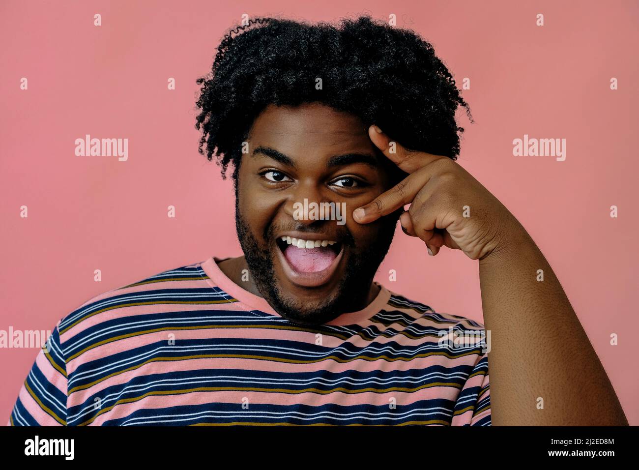 young happy african american man posing in the studio over pink ...