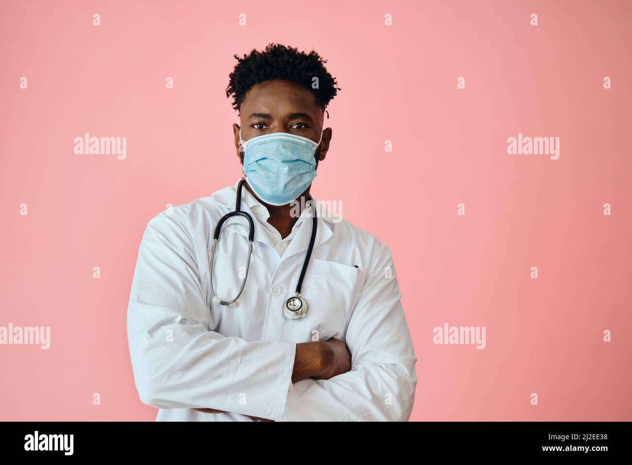 Portrait of Afro male doctor wearing protective face mask standing with ...