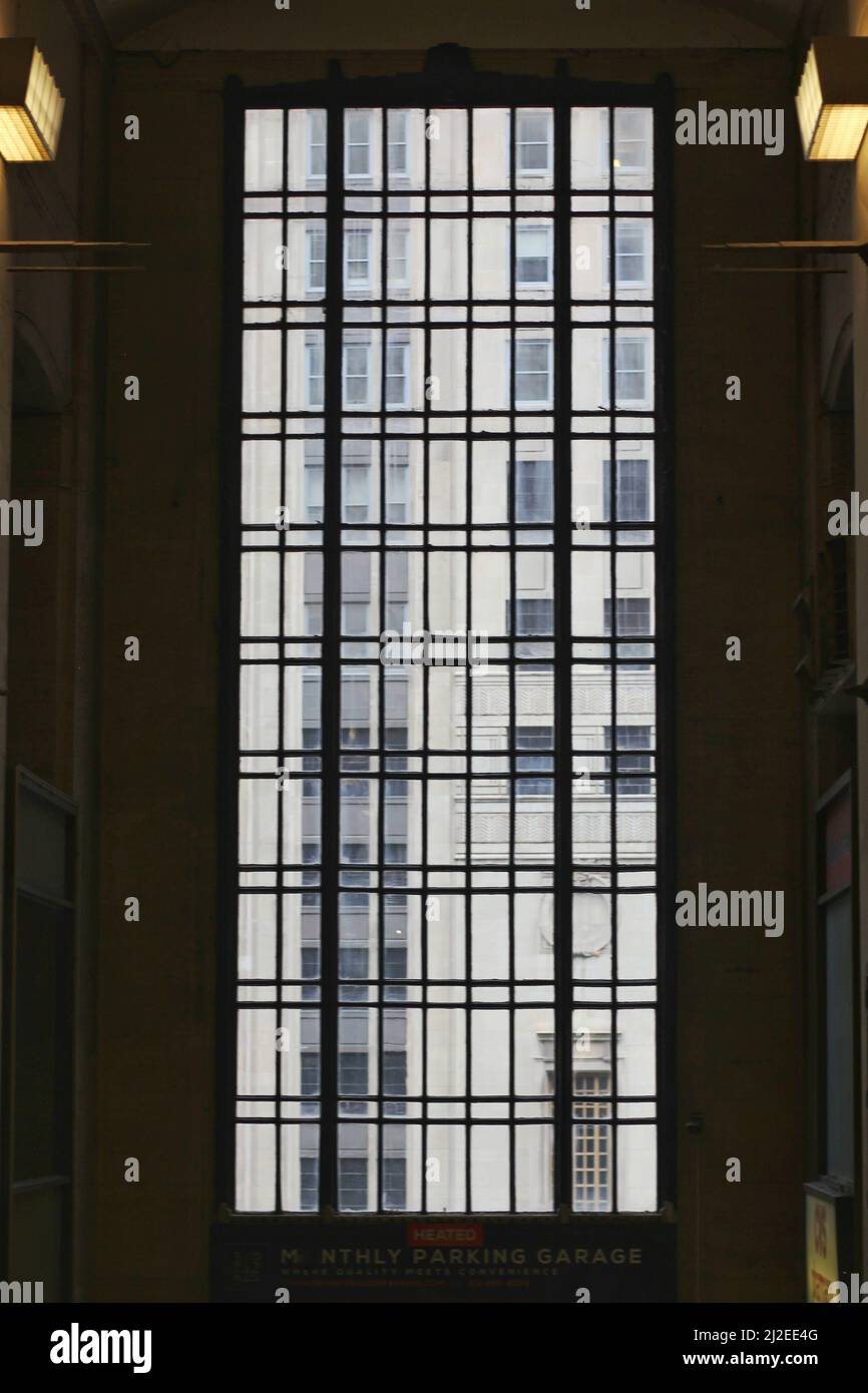 A very tall and huge window with a skyscraper showing thru the glazing ...