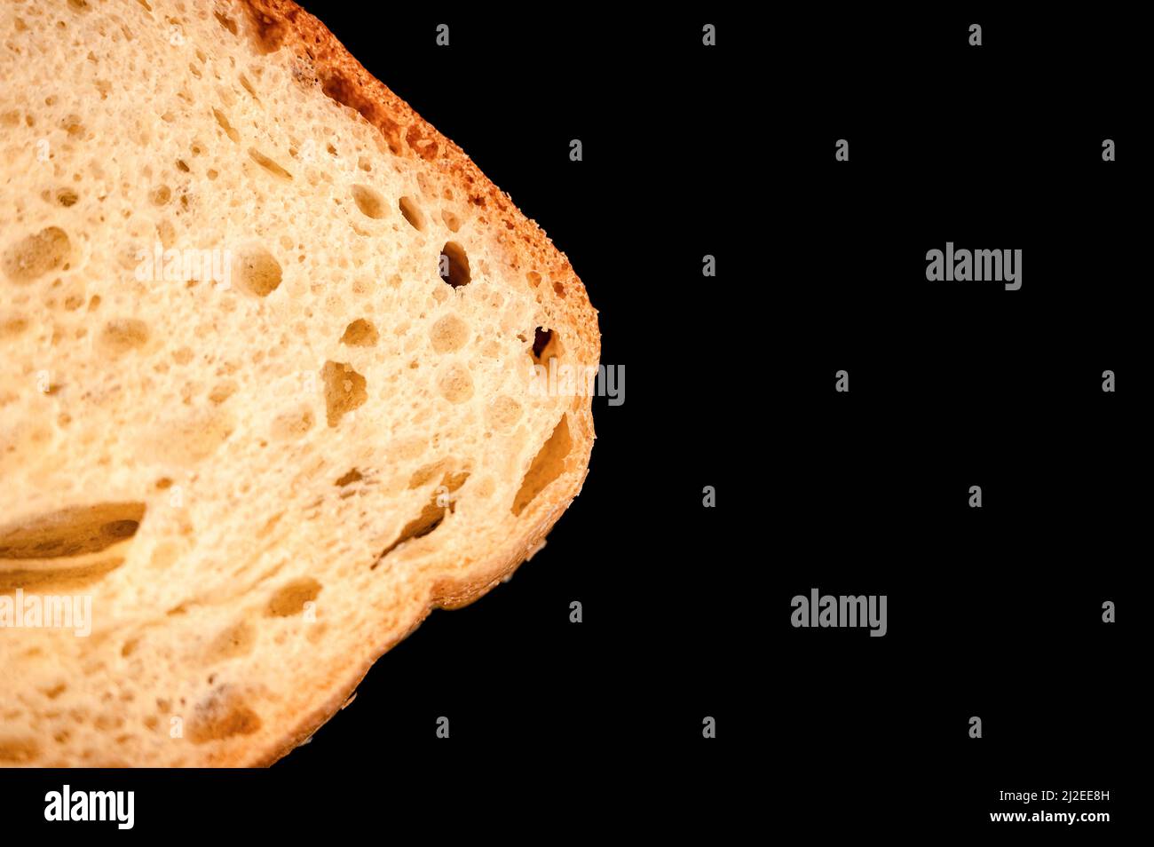 slice of white bread close up isolated on a black background. rough ...