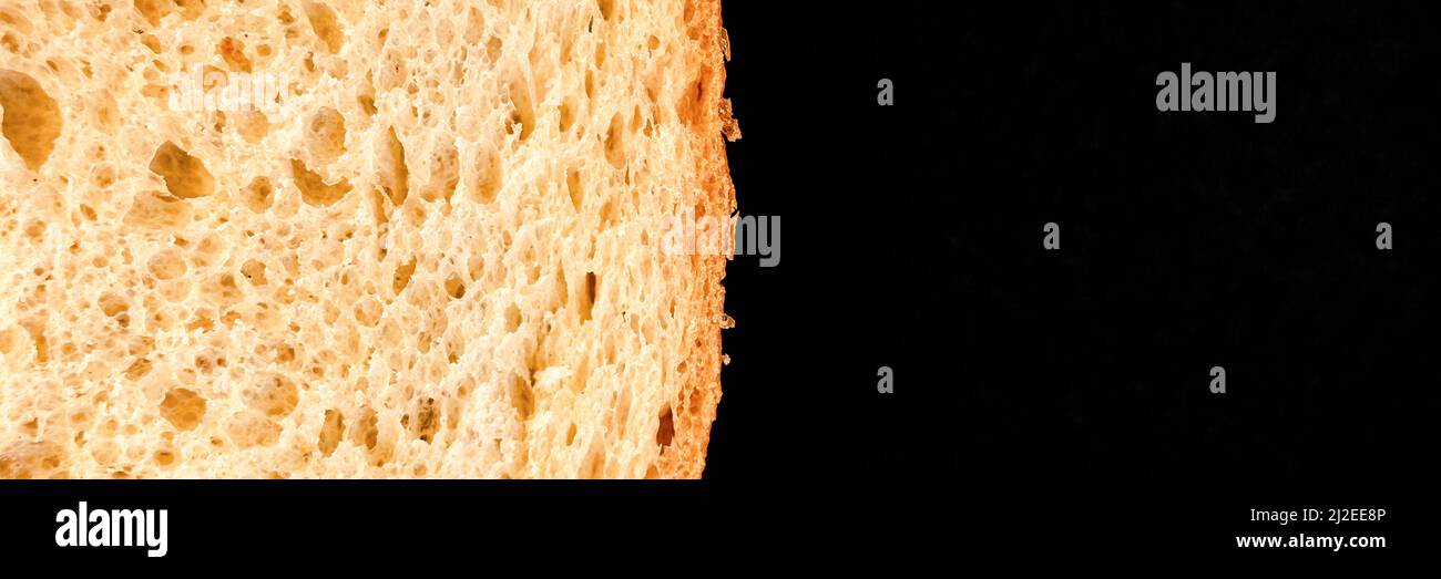 slice of white bread close up isolated on a black background. rough ...