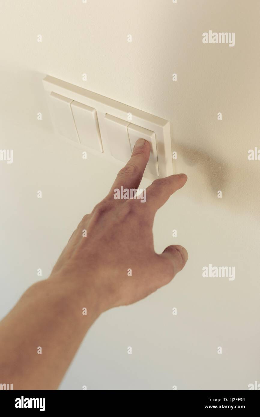 Hand presses a light switch with a finger Stock Photo - Alamy