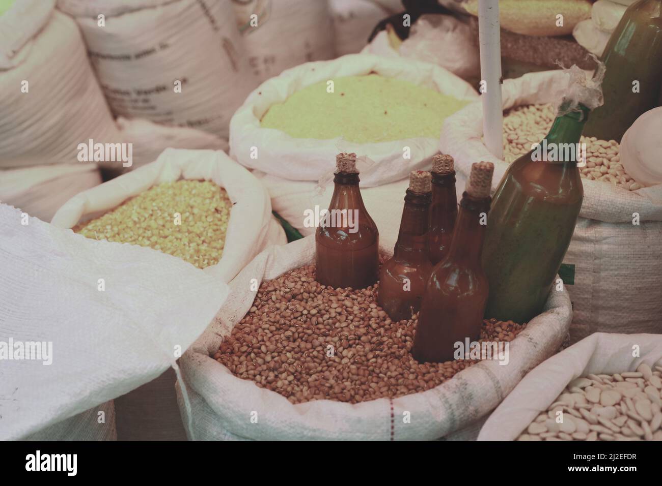 Different organic raw seeds in a sack with glass bottles stuck in one ...