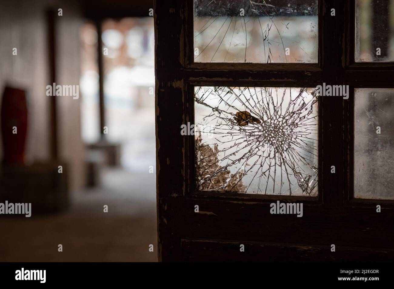 Broken glass or shattered window in a wooden frame of a door. Dark ...