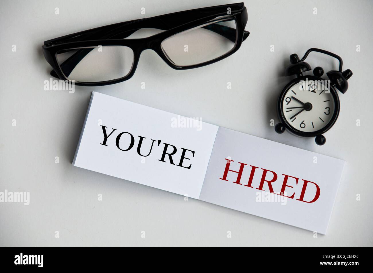 You're hired text on notepad with alarm clock and glasses Stock Photo ...
