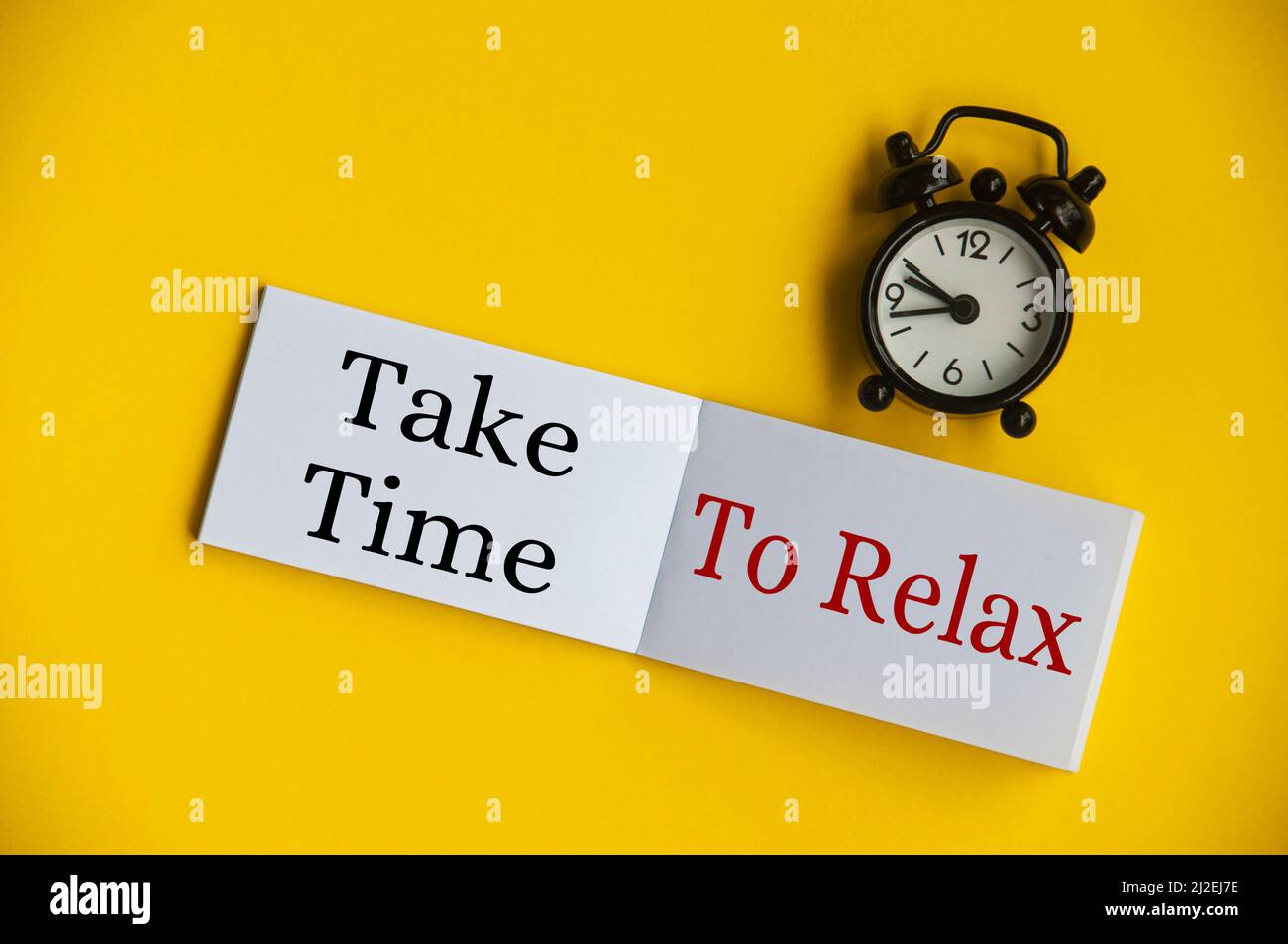 Take time to relax text on notepad with alarm clock on yellow ...