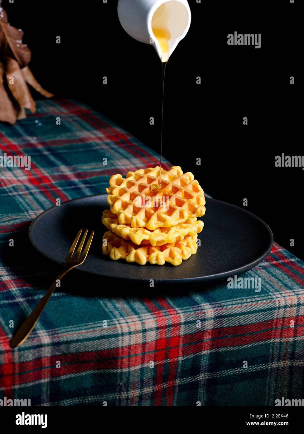 A honey dripping on Belgian waffles on a striped carpet isolated in ...