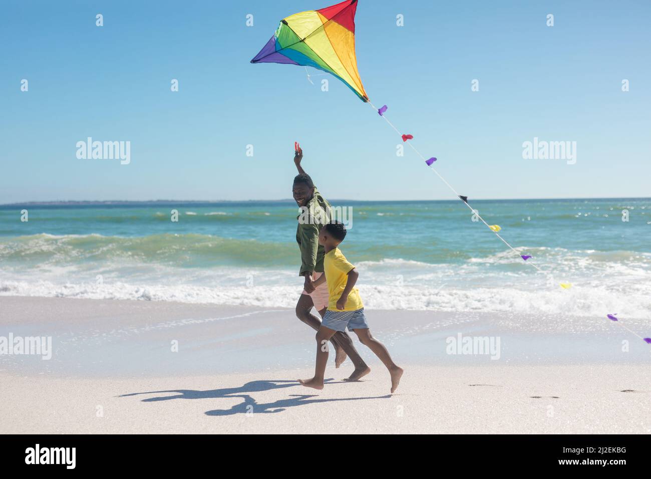 African American Father And Son Holding Hands While Running With Kite