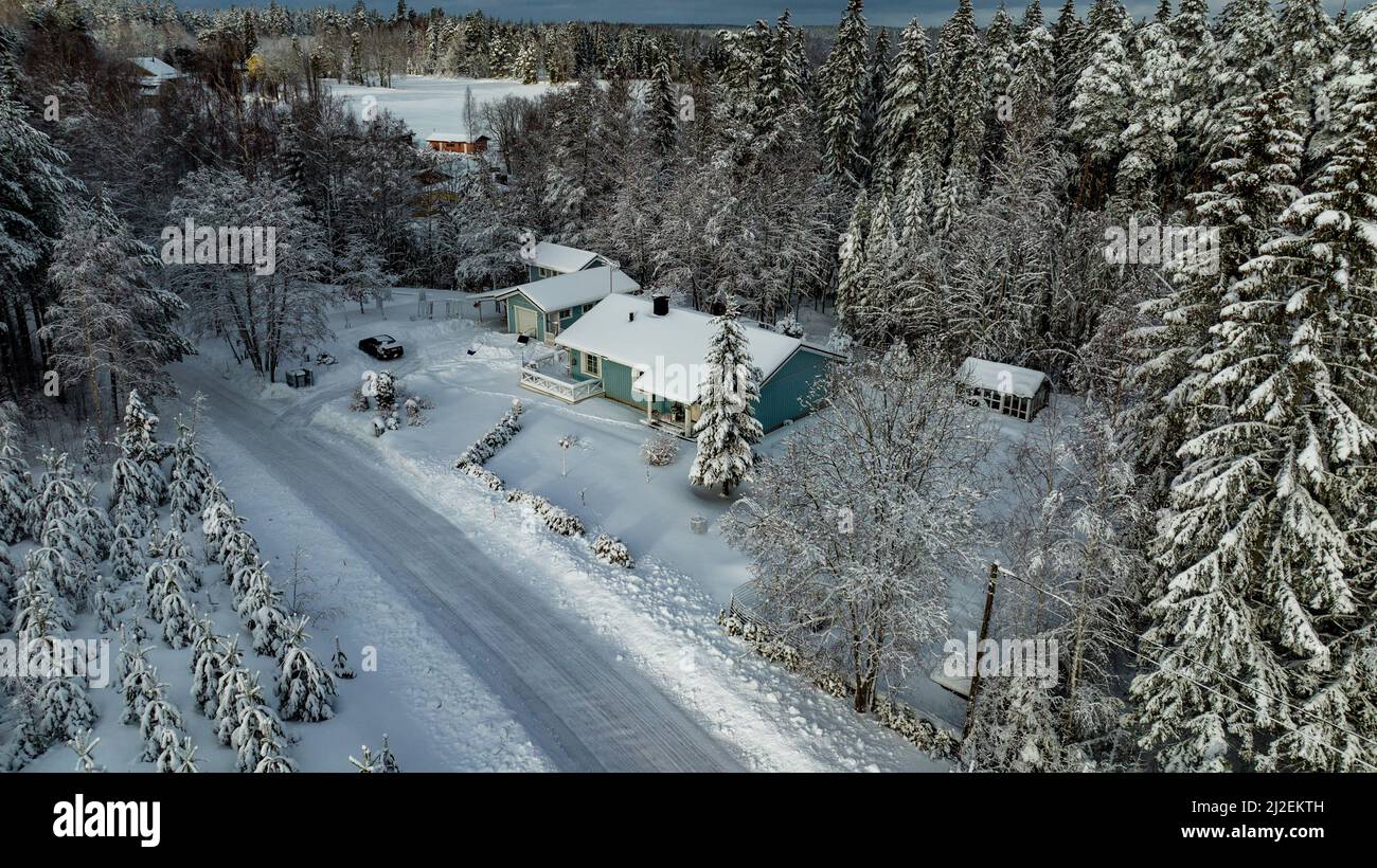 Aerial view above a snow covered house in middle of frosty forest Stock ...