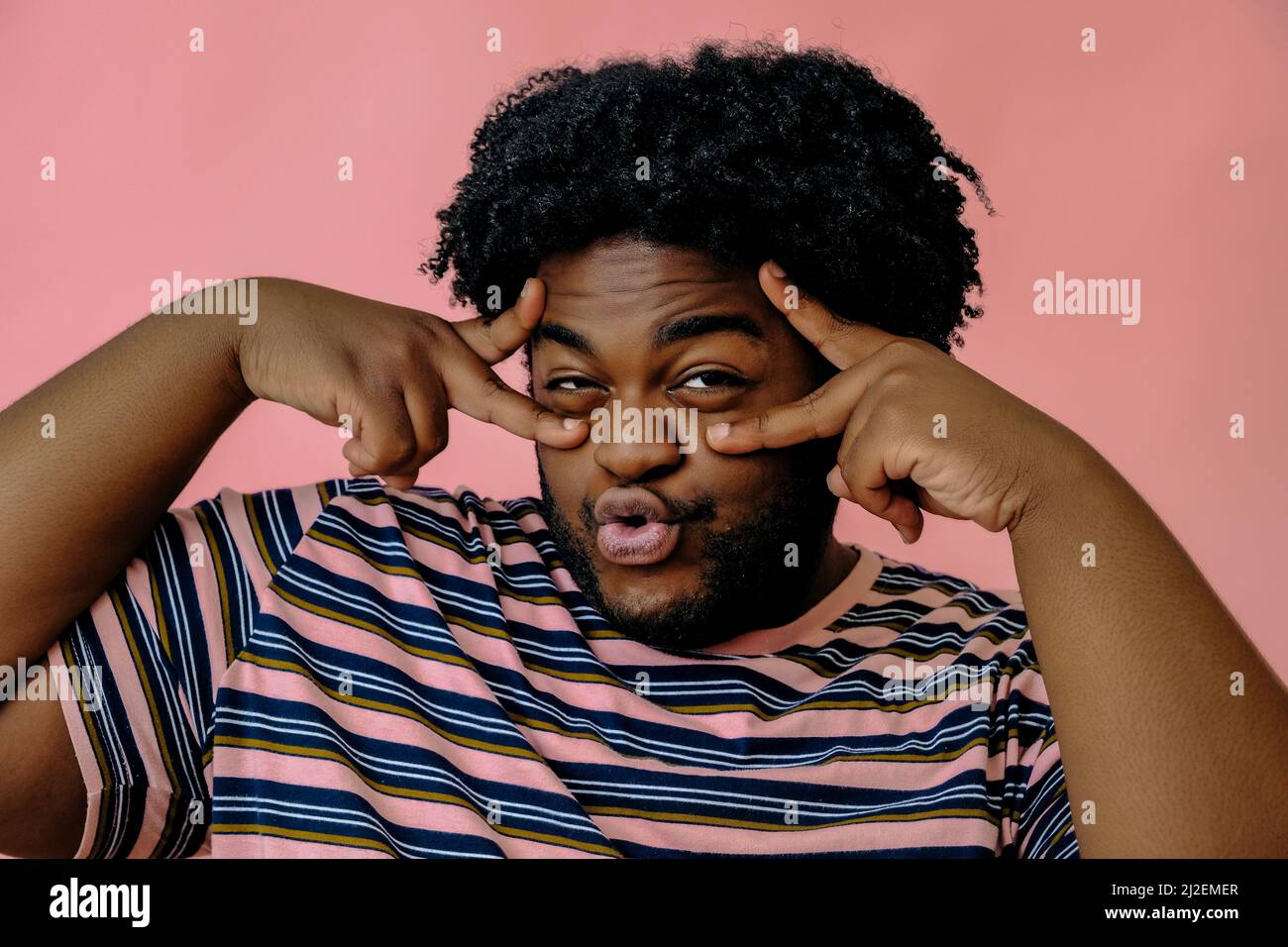 young happy african american man posing in the studio over pink ...