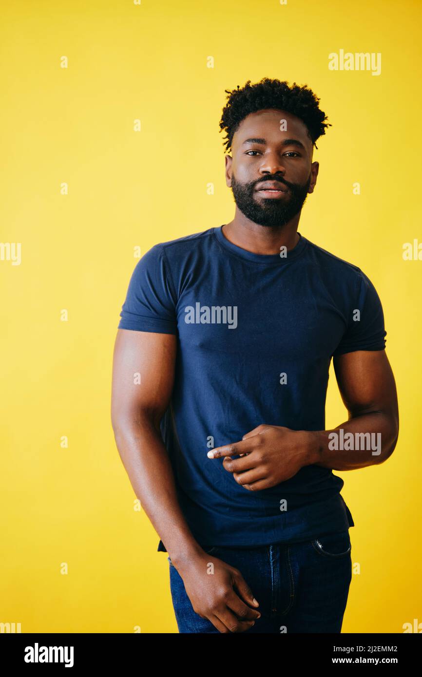 Handsome bearded man with muscular build standing against yellow ...