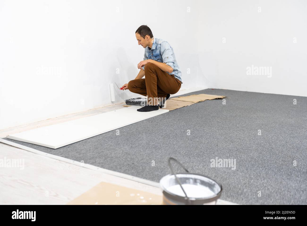 Back view of painter painting a wall with paint roller, with copy space ...
