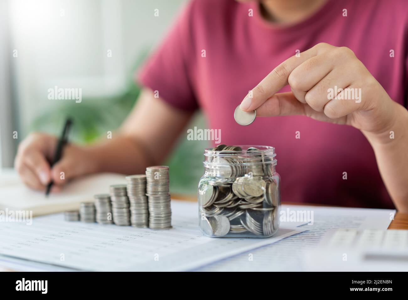 Saving concept the woman putting the coins into the bottle and taking ...