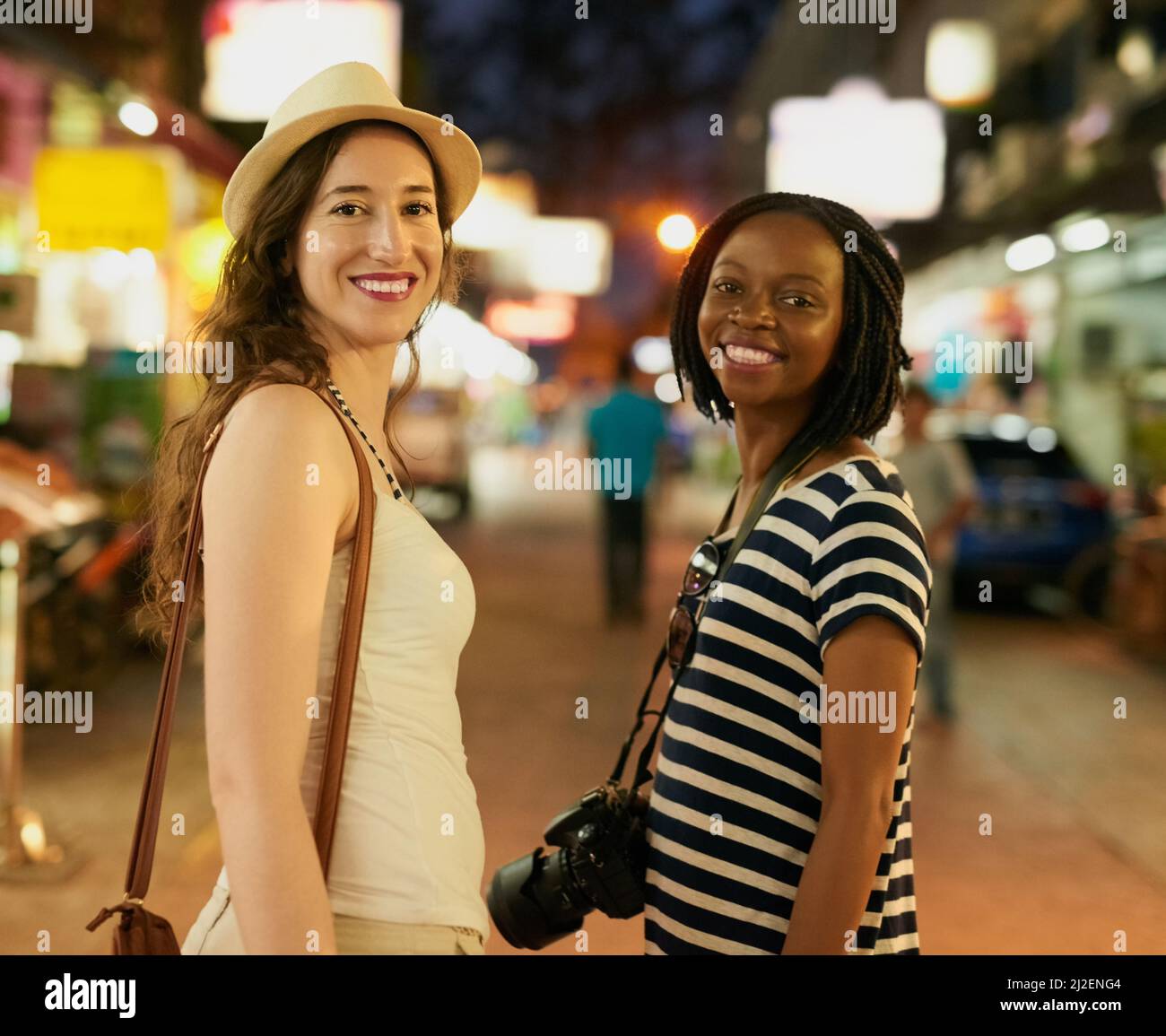 This city comes alive at night. Portrait of two happy young friends ...