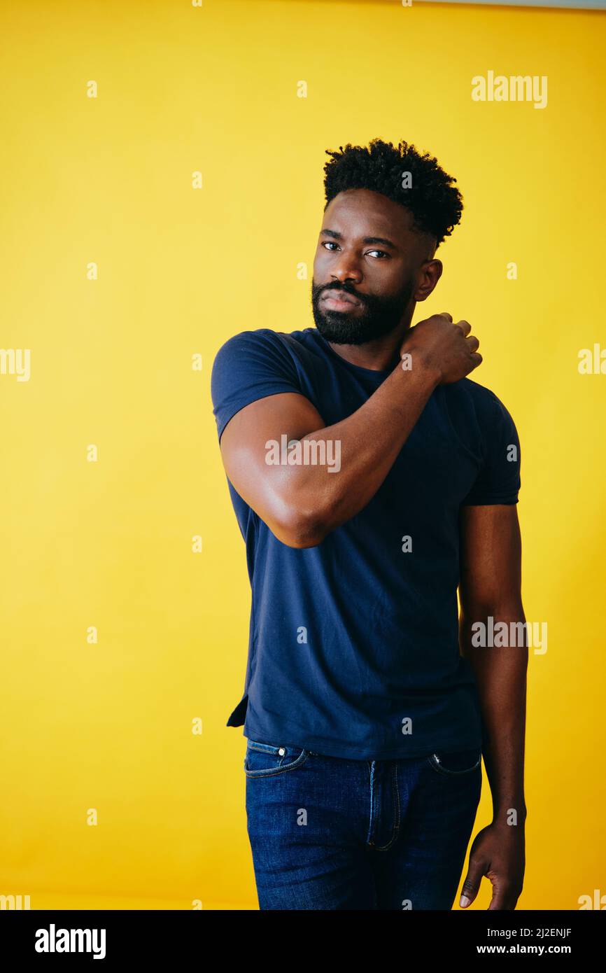 Handsome bearded man with muscular build standing against yellow ...