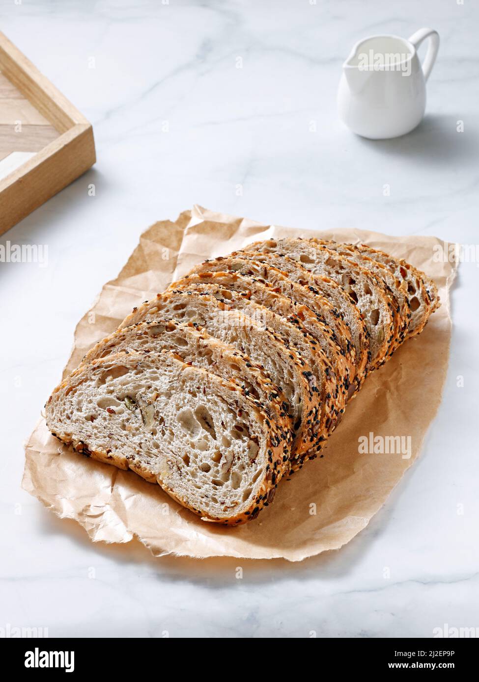 A view of sliced bread on white table with sauce boat in background ...