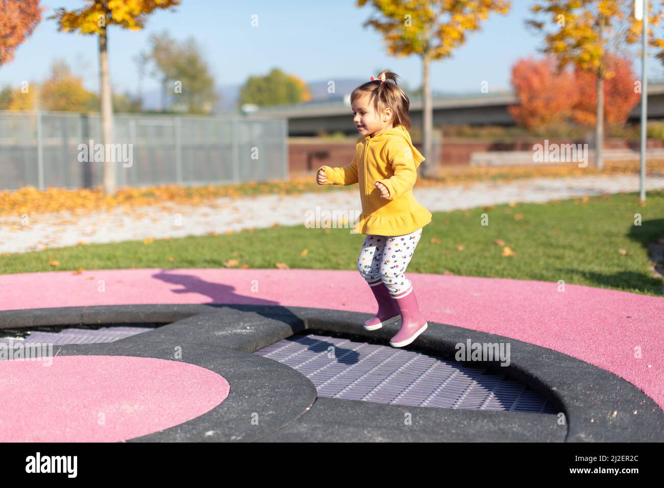 High-key image of 2-years old girl jumping on trampoline enjoying the ...