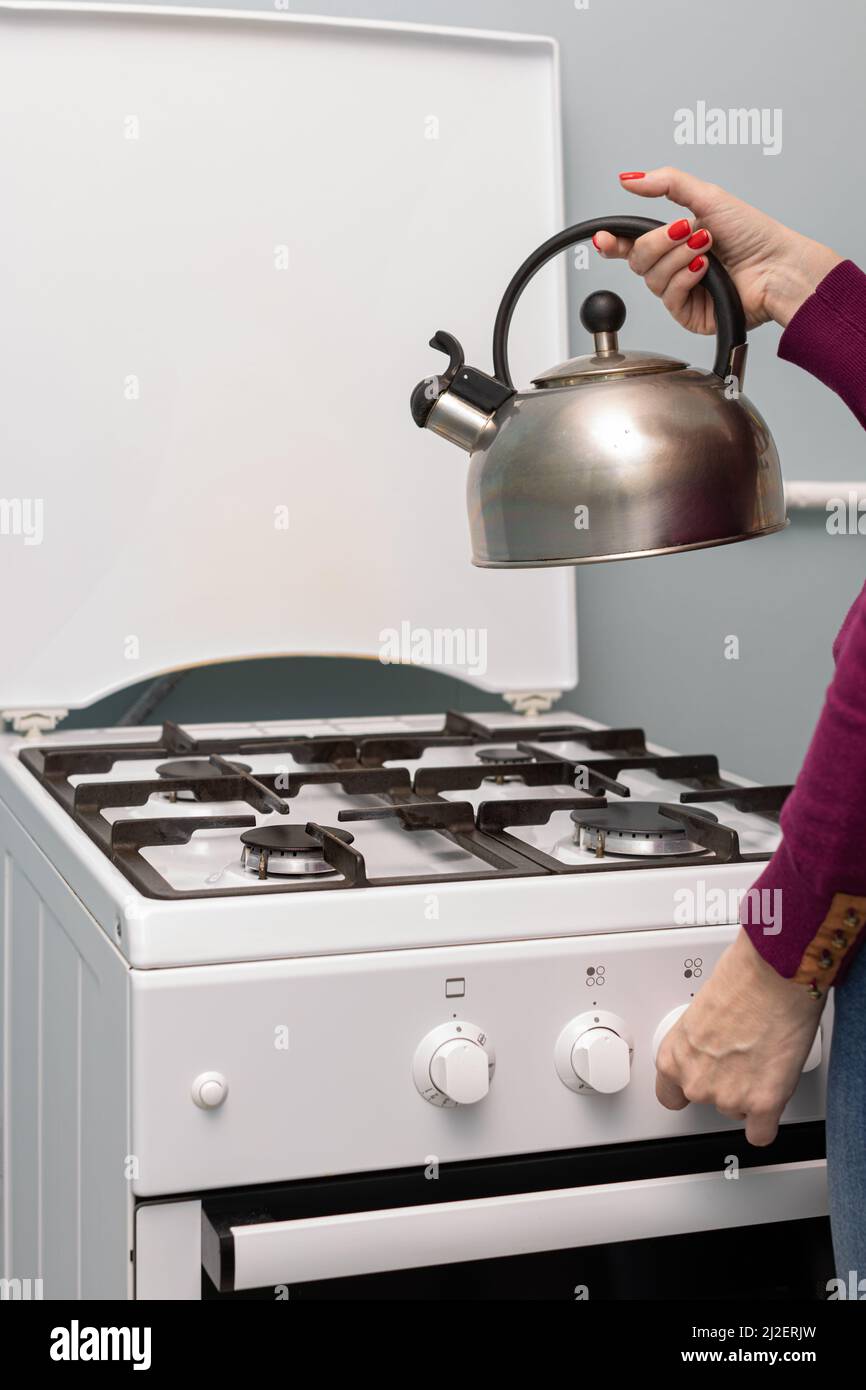 female hand puts a metal kettle on a gas burner. High quality photo ...