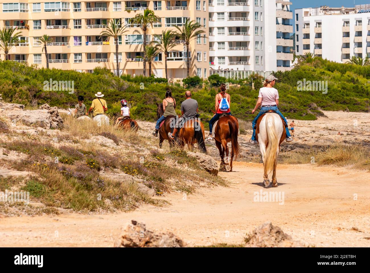 A group of people riding horses in the town of Cala Millor, Majorca ...