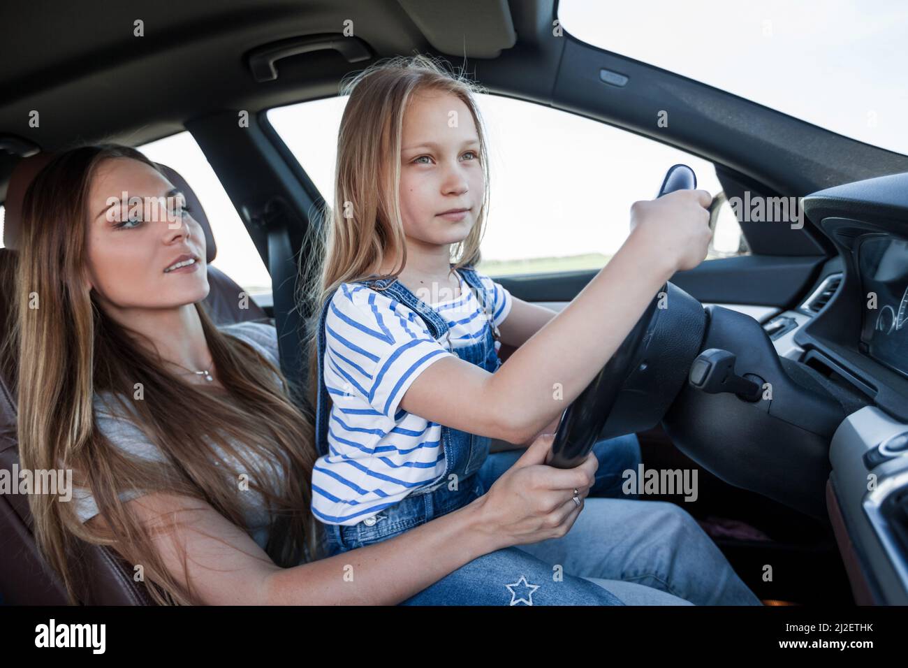 mom and her daughter sitting at the wheel of a car Stock Photo - Alamy