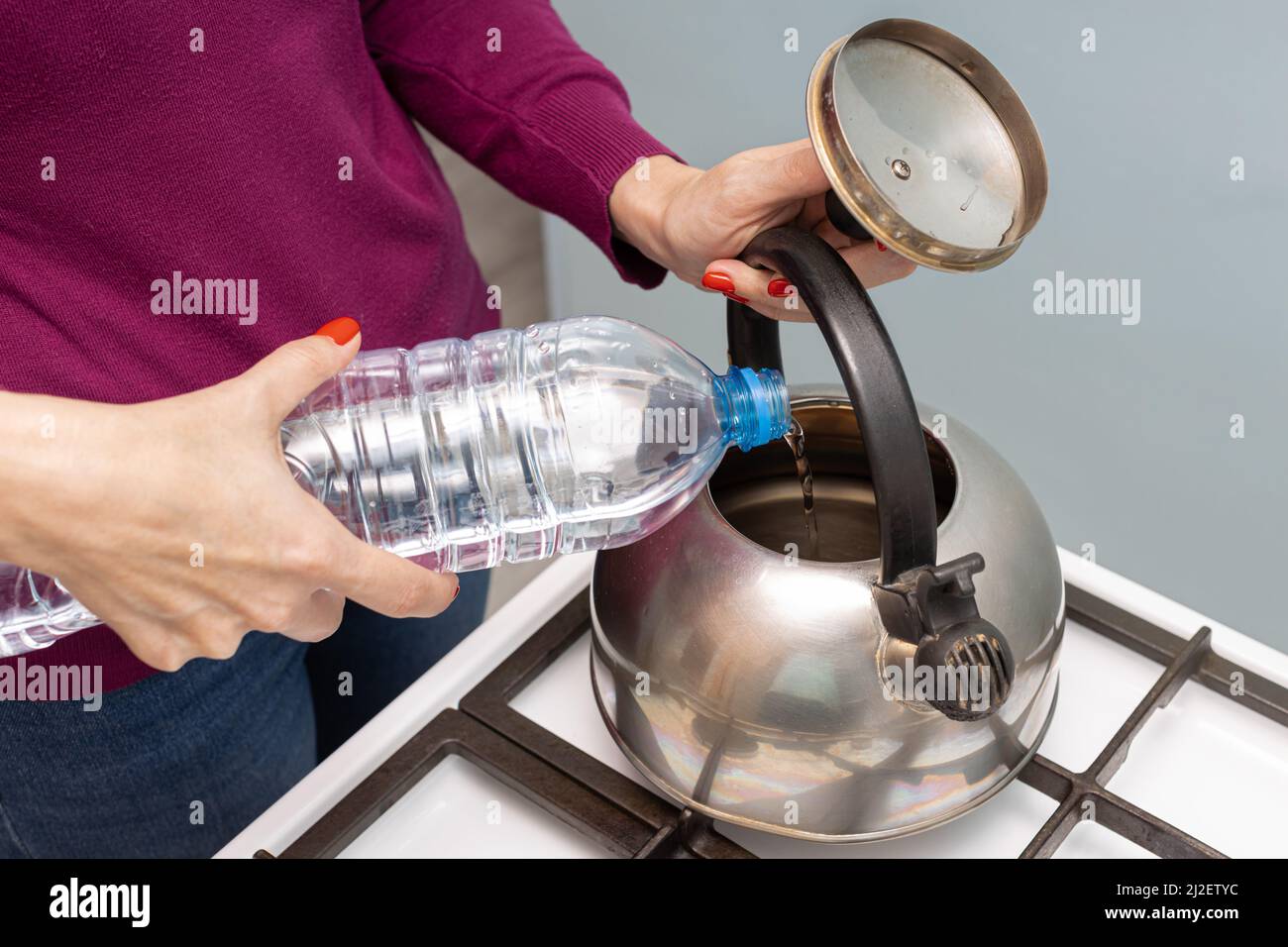 woman pouring clean water from a bottle into a kettle. High quality ...