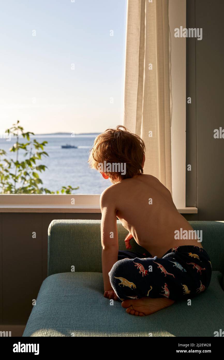 Boy Looking out window to ocean Stock Photo - Alamy