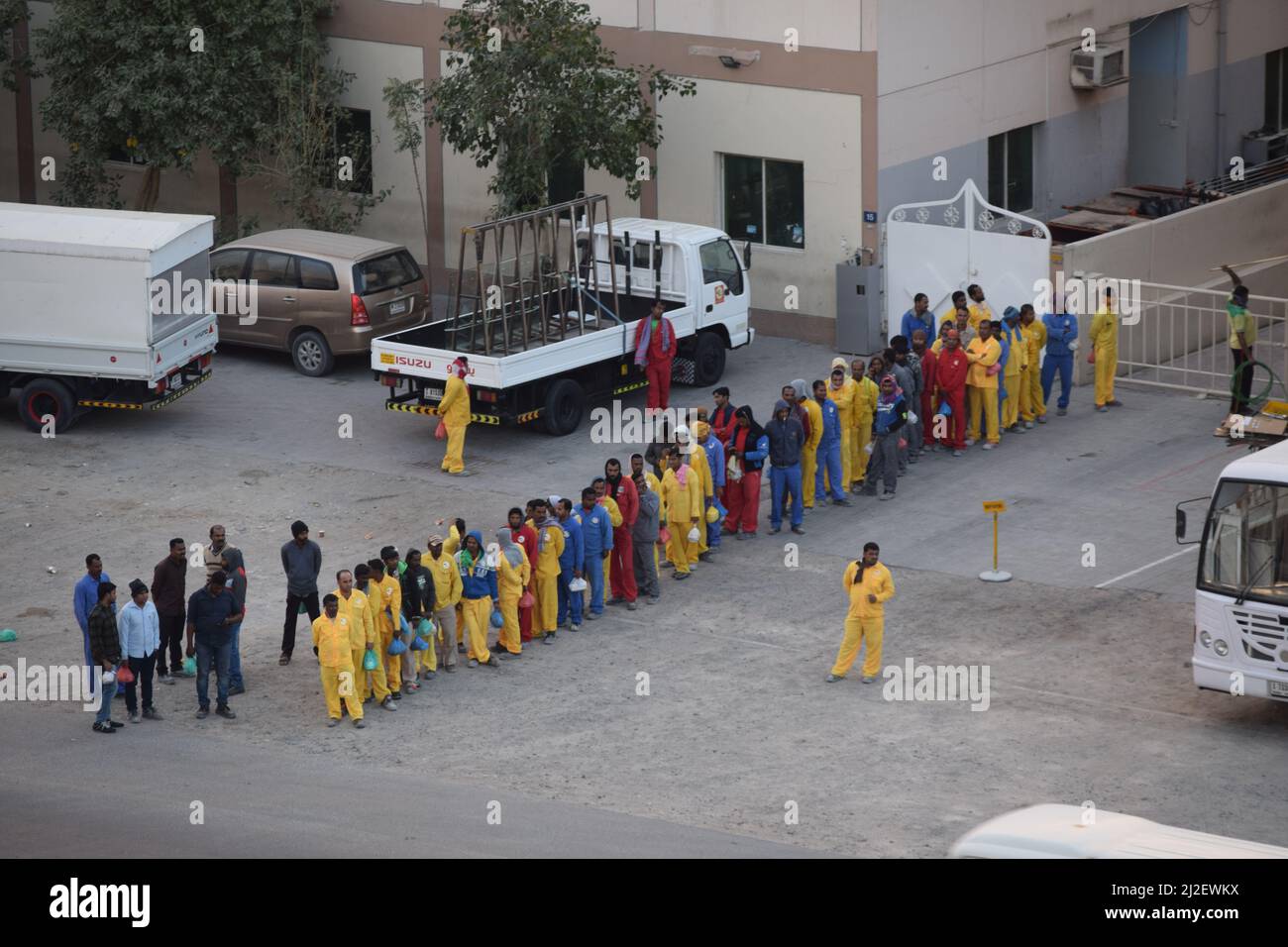 Construction workers in a line waiting for their transportation to go ...