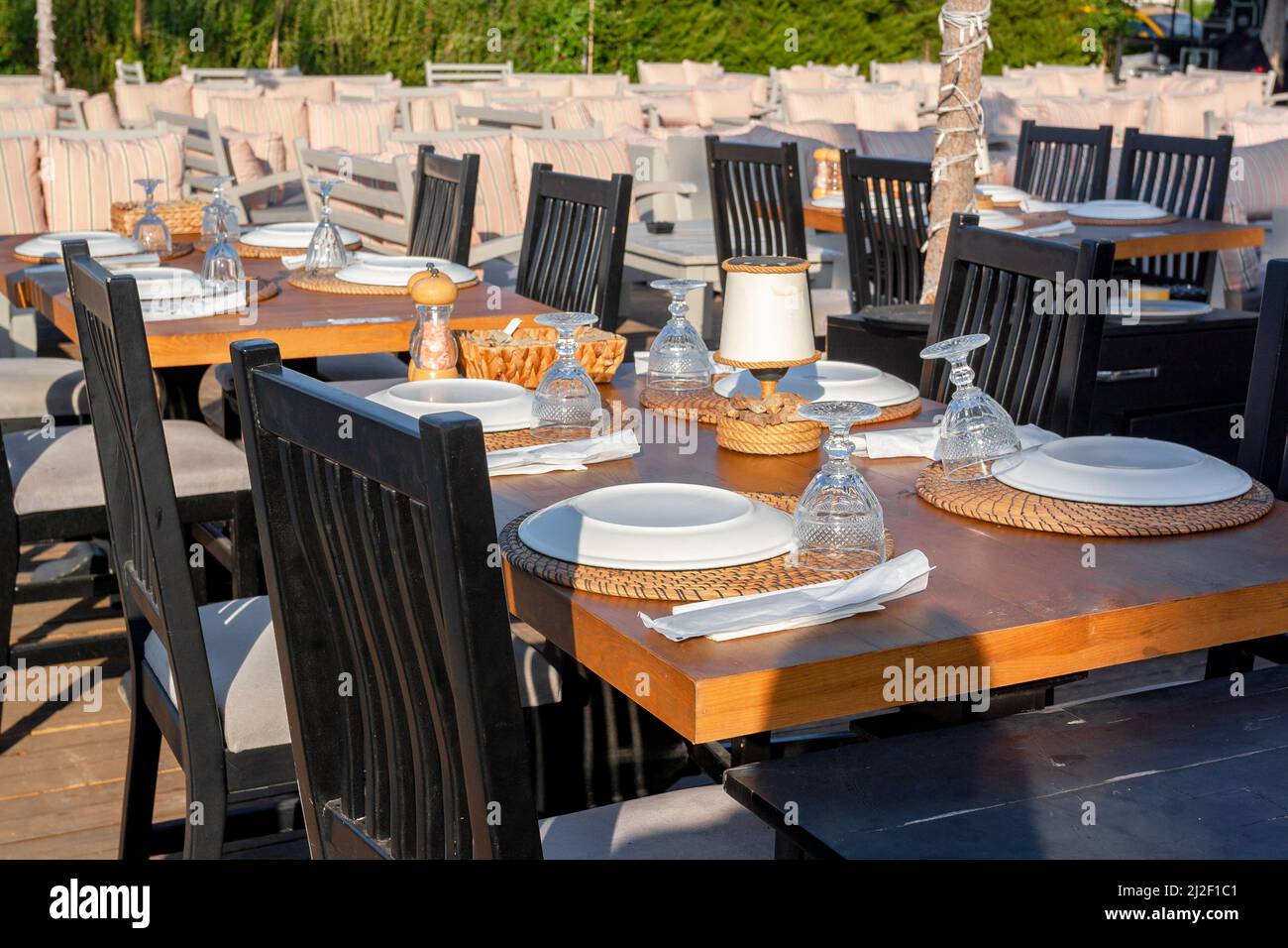 Many wooden tables in cafe with plates and glasses are waiting for ...