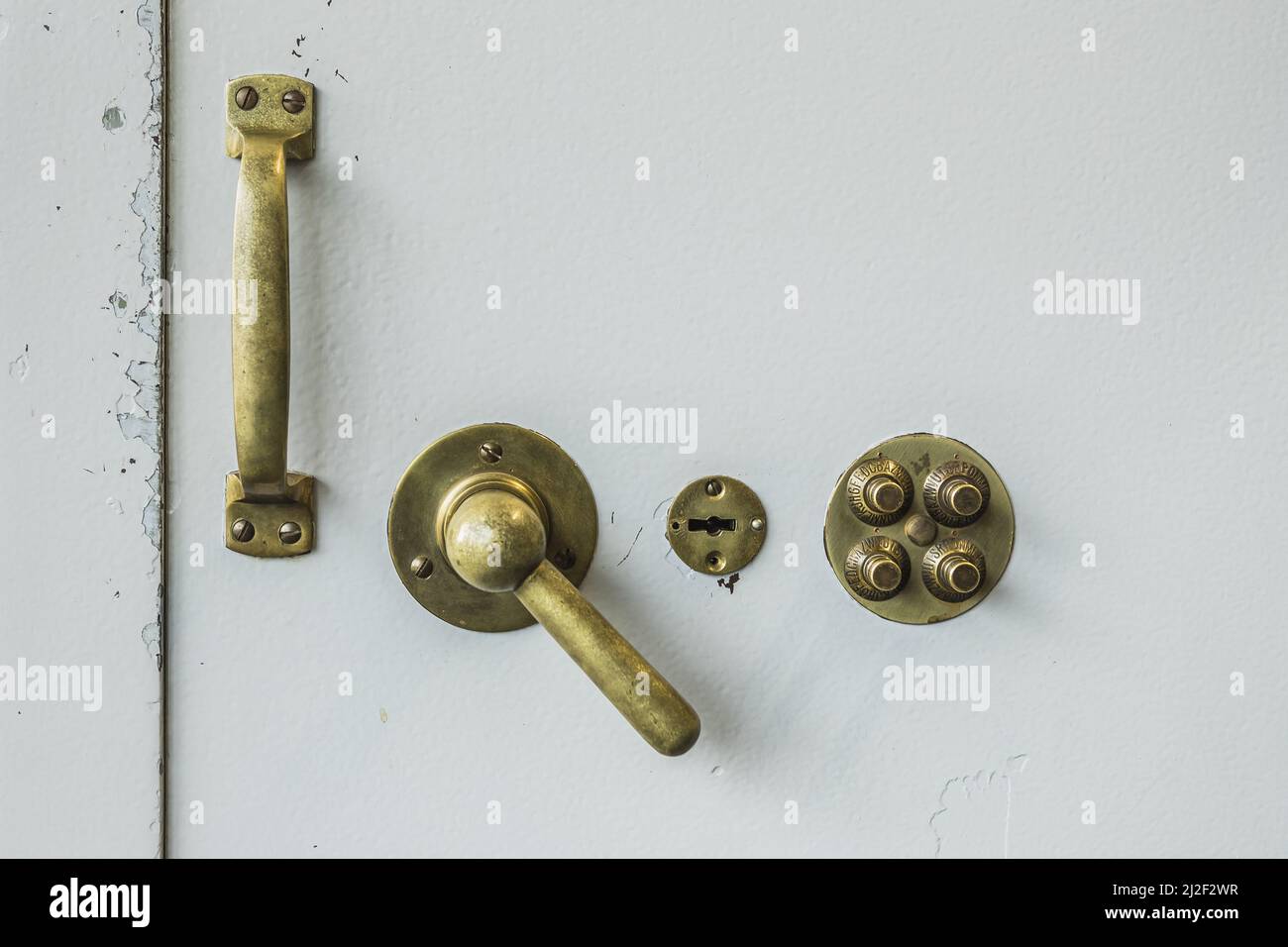 A closeup shot of door handles and locks on an old white door of a ...