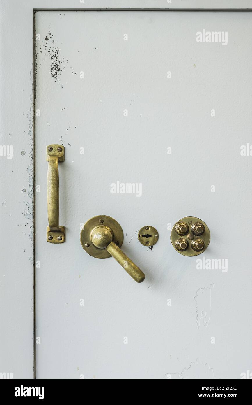 A vertical shot of a door of a safety box with golden handles and locks ...