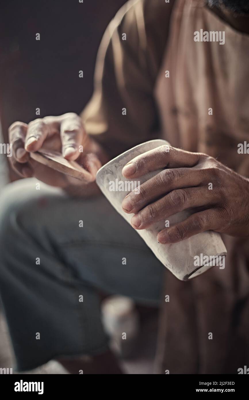 the artist polishing rough edges of a ceramic pot with a sponge in ...