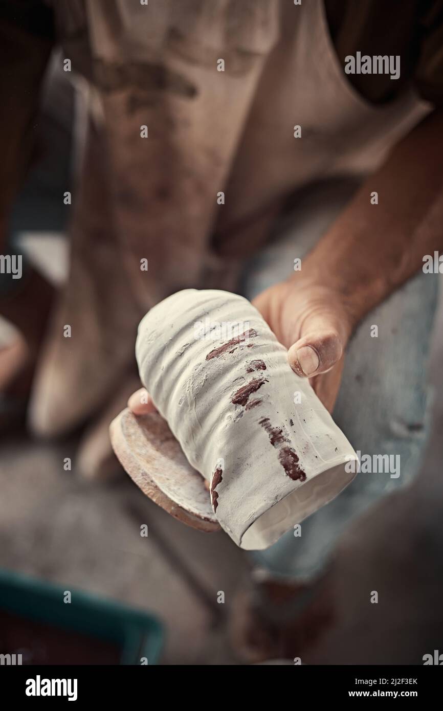 the artist polishing rough edges of a ceramic pot with a sponge in ...