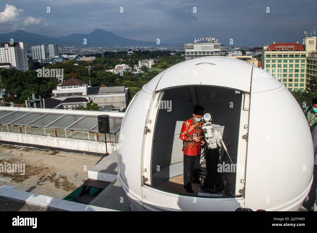 An Indonesian Muslim uses binoculars to see the new crescent moon and ...