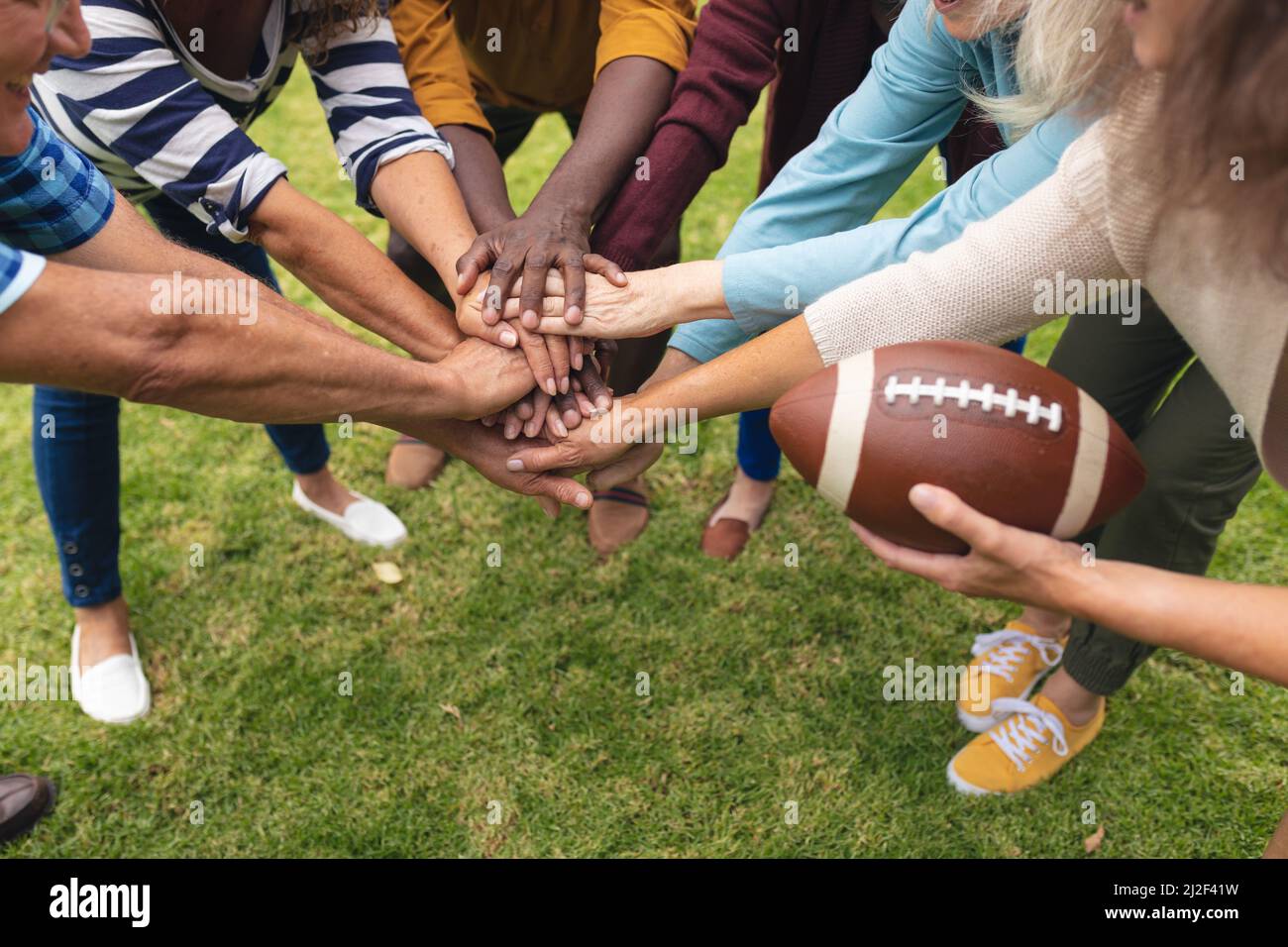 Multiracial senior male and female friends stacking hands while playing ...