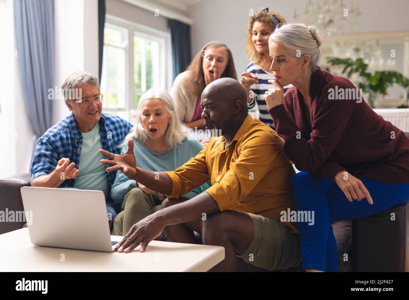 Senior african american man showing laptop to caucasian friends during ...