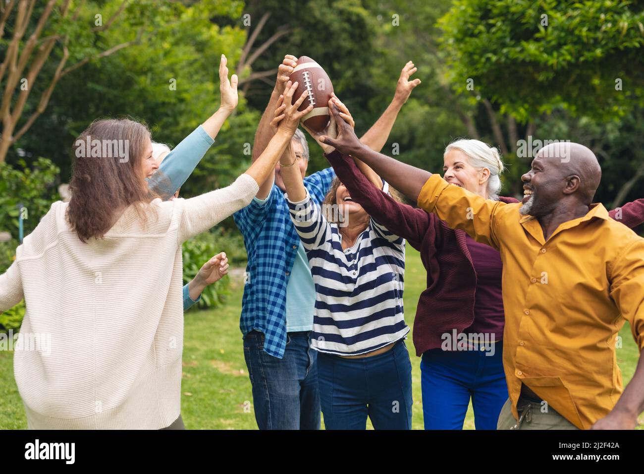 Happy multiracial active senior male and female friends holding rugby ...