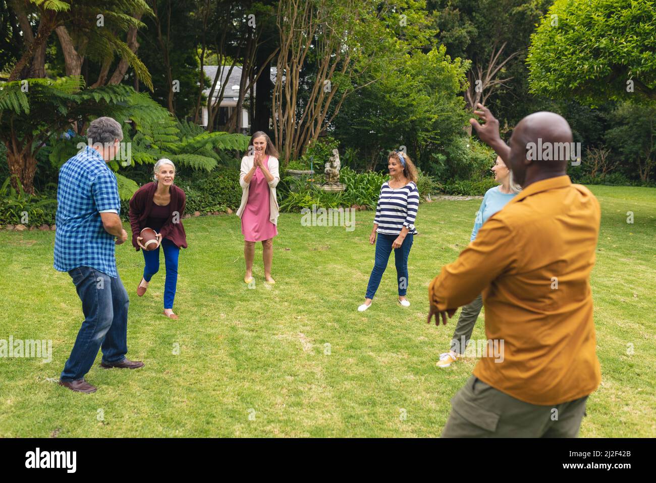 Multiracial active senior male and female friends playing rugby in ...