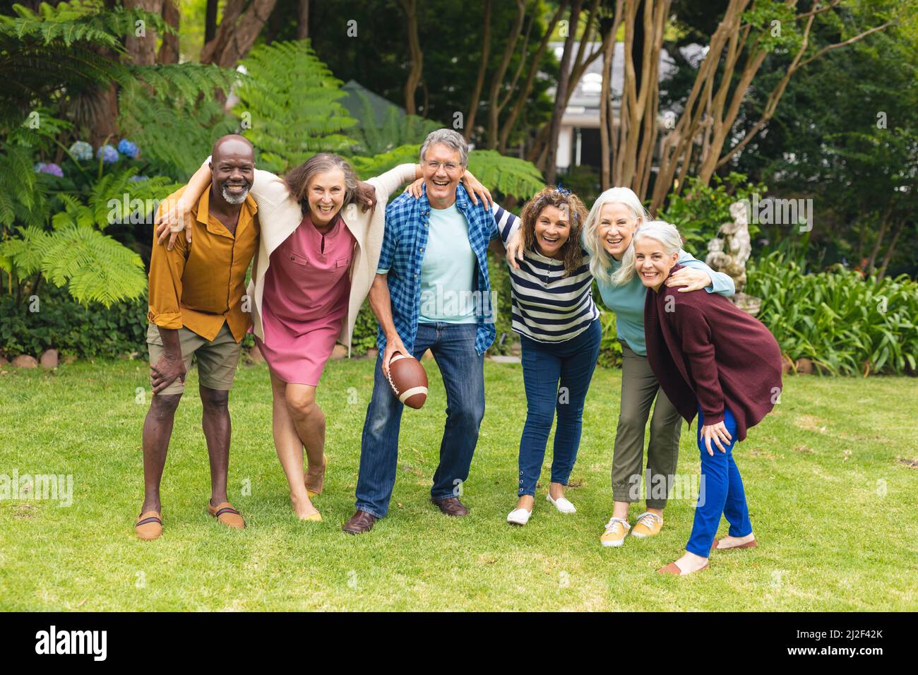 Portrait of happy multiracial senior male and female friends with arms ...
