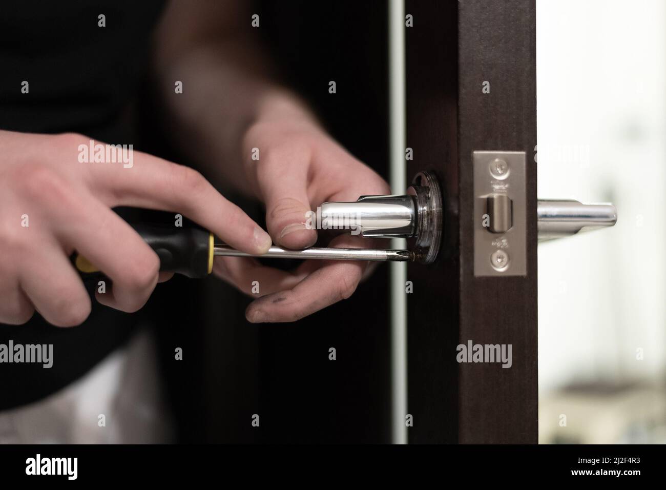 A man installs a handle on a wooden door Stock Photo - Alamy