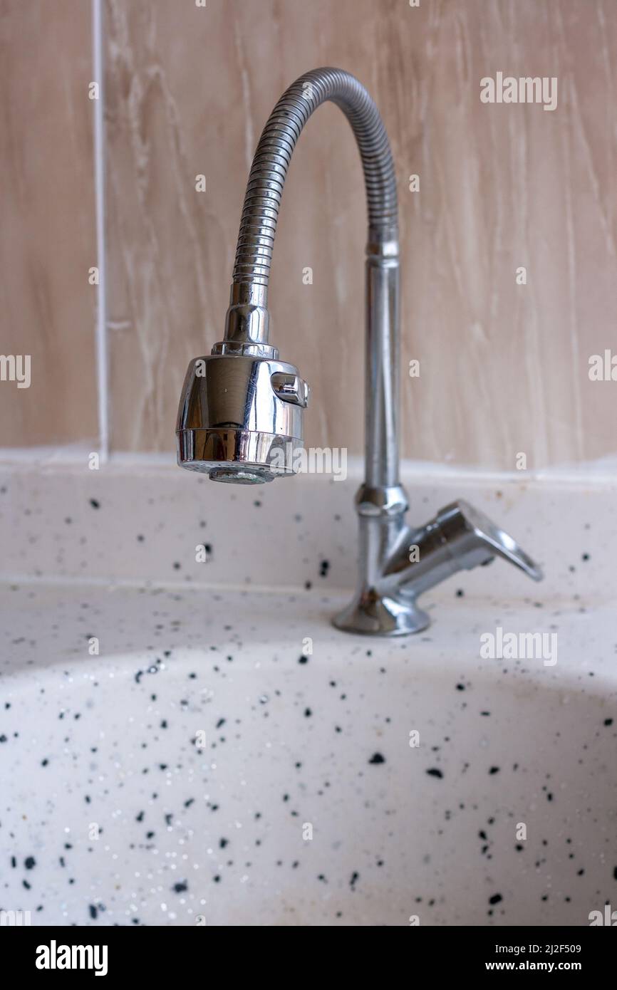 Large flexible faucet head and marble sink. Selective focus on head ...