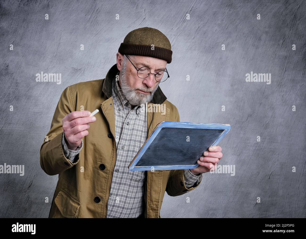 bearded senior man wearing glasses and docker cap is writing with white ...