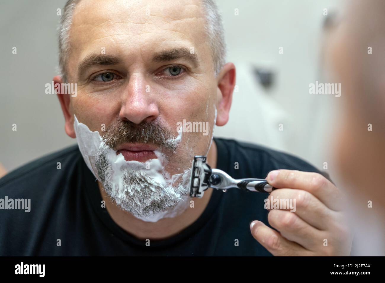 Middle aged handsome man shaving his beard in bathroom Stock Photo - Alamy