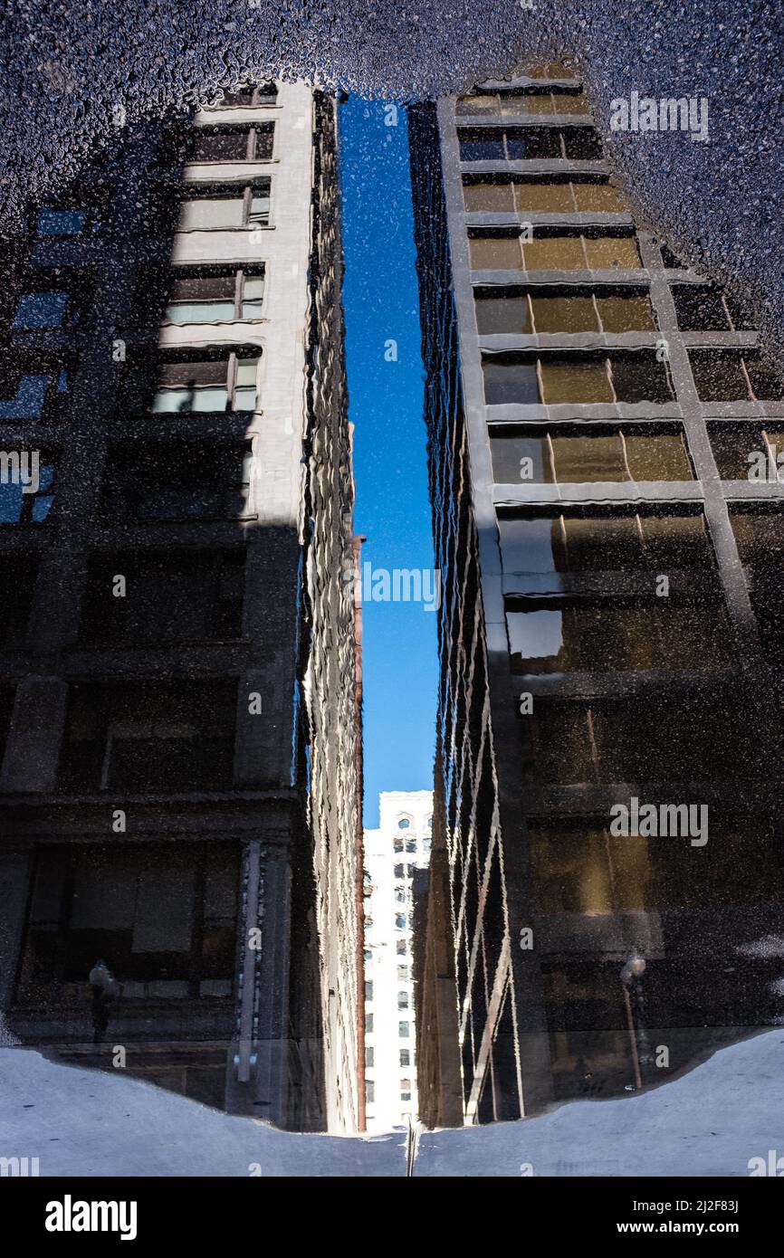 A view of the reflections of the modern buildings on a puddle in the ...