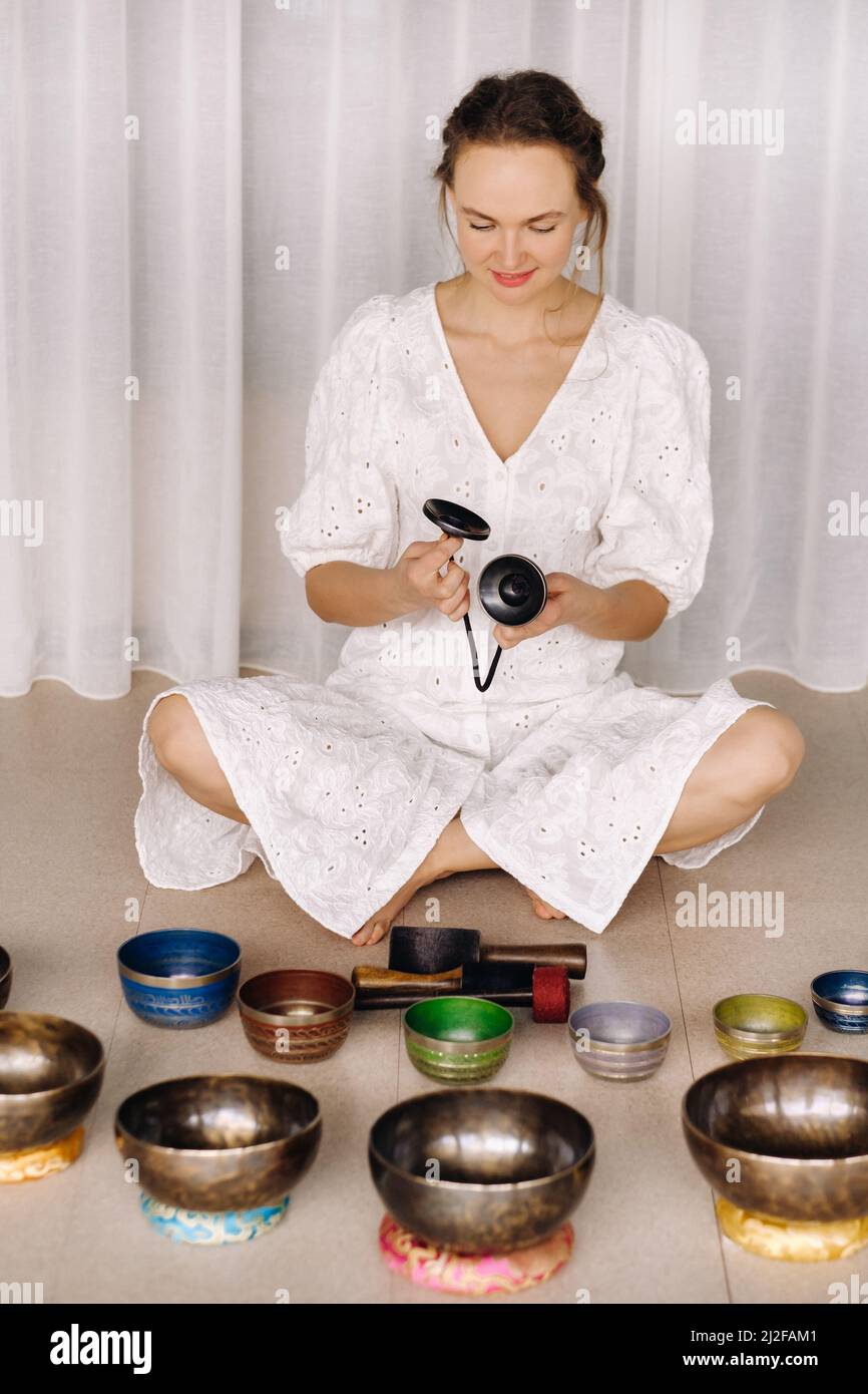 Portrait of a female yoga teacher playing a Tibetan bowl or singing a ...