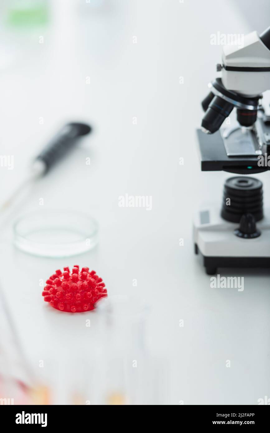 red coronavirus bacteria model and blurred microscope in bio laboratory ...
