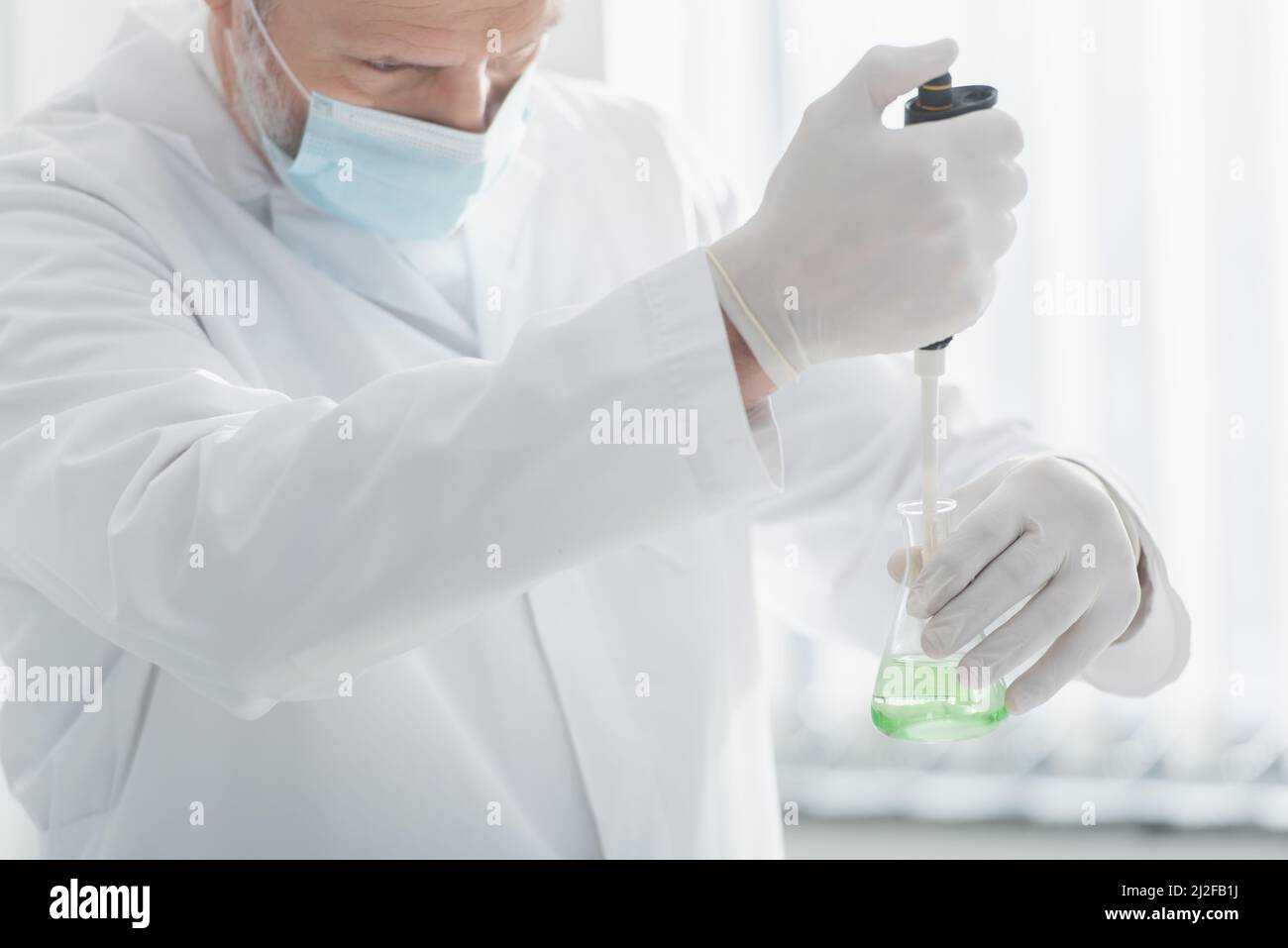 scientist in medical mask and latex gloves holding micropipette and ...