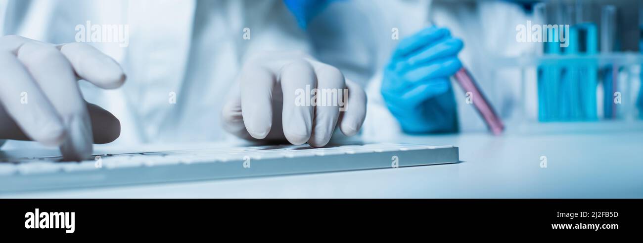 partial view of scientist in latex gloves typing on computer keyboard ...