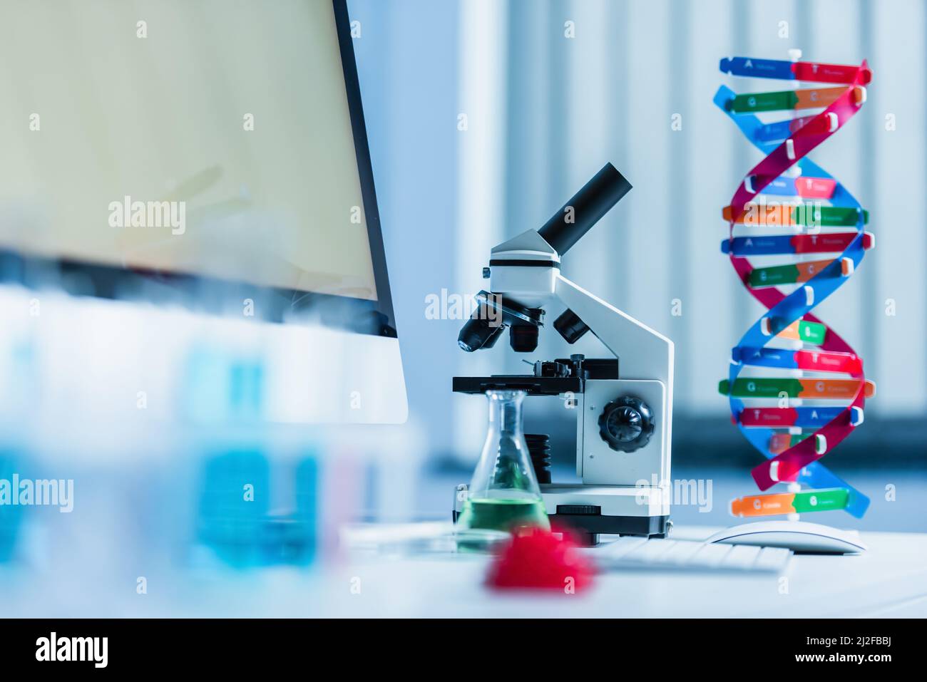 microscope and dna model near monitor with grey screen on blurred ...