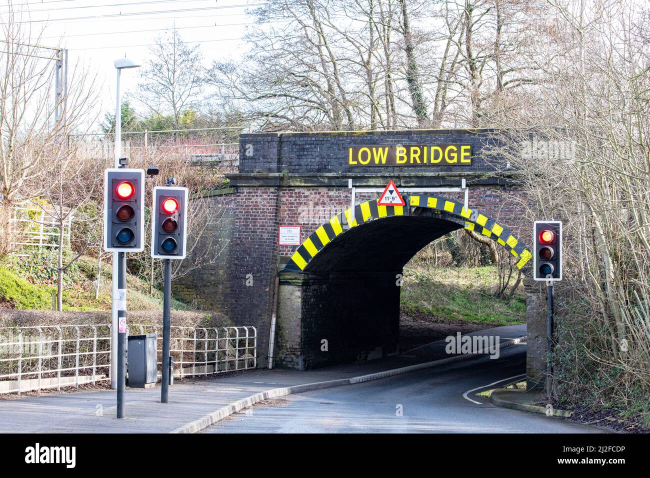 3 traffic lights in front of a low bridge with warning sign in Cheshire ...
